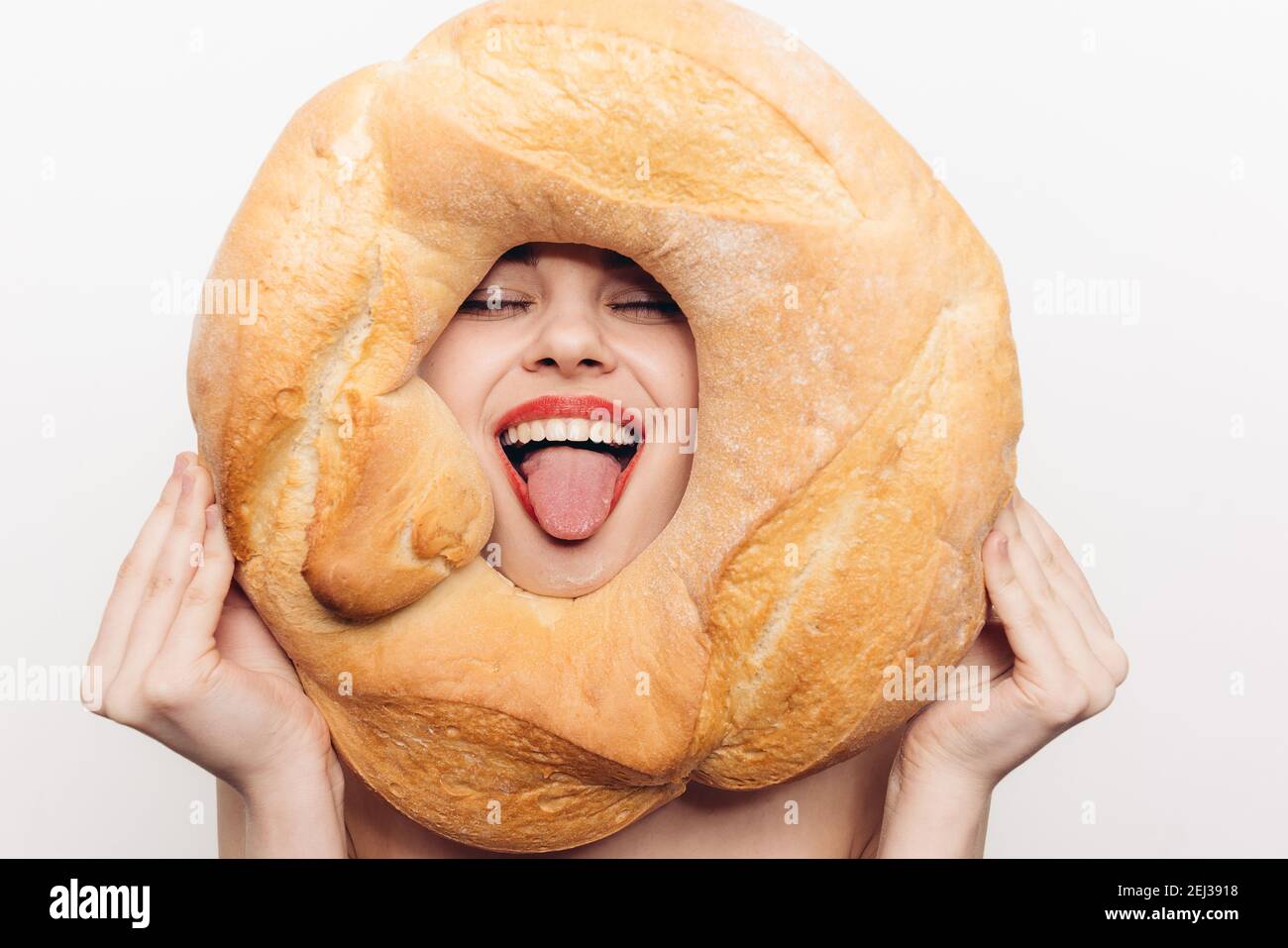 happy woman with bright makeup holds a round loaf of bread in her hand ...