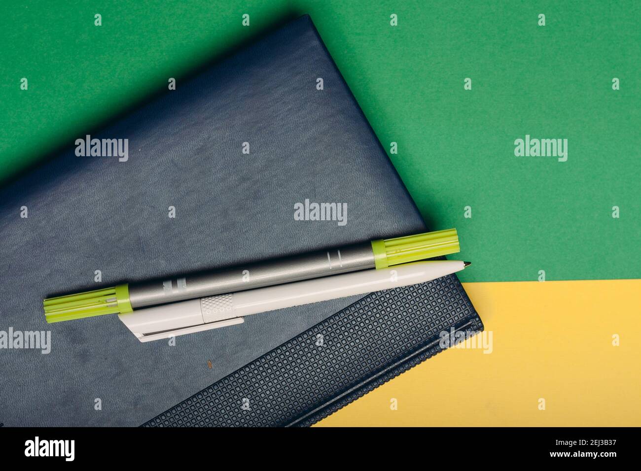 notepad with markers and pens on yellow green background and office ...