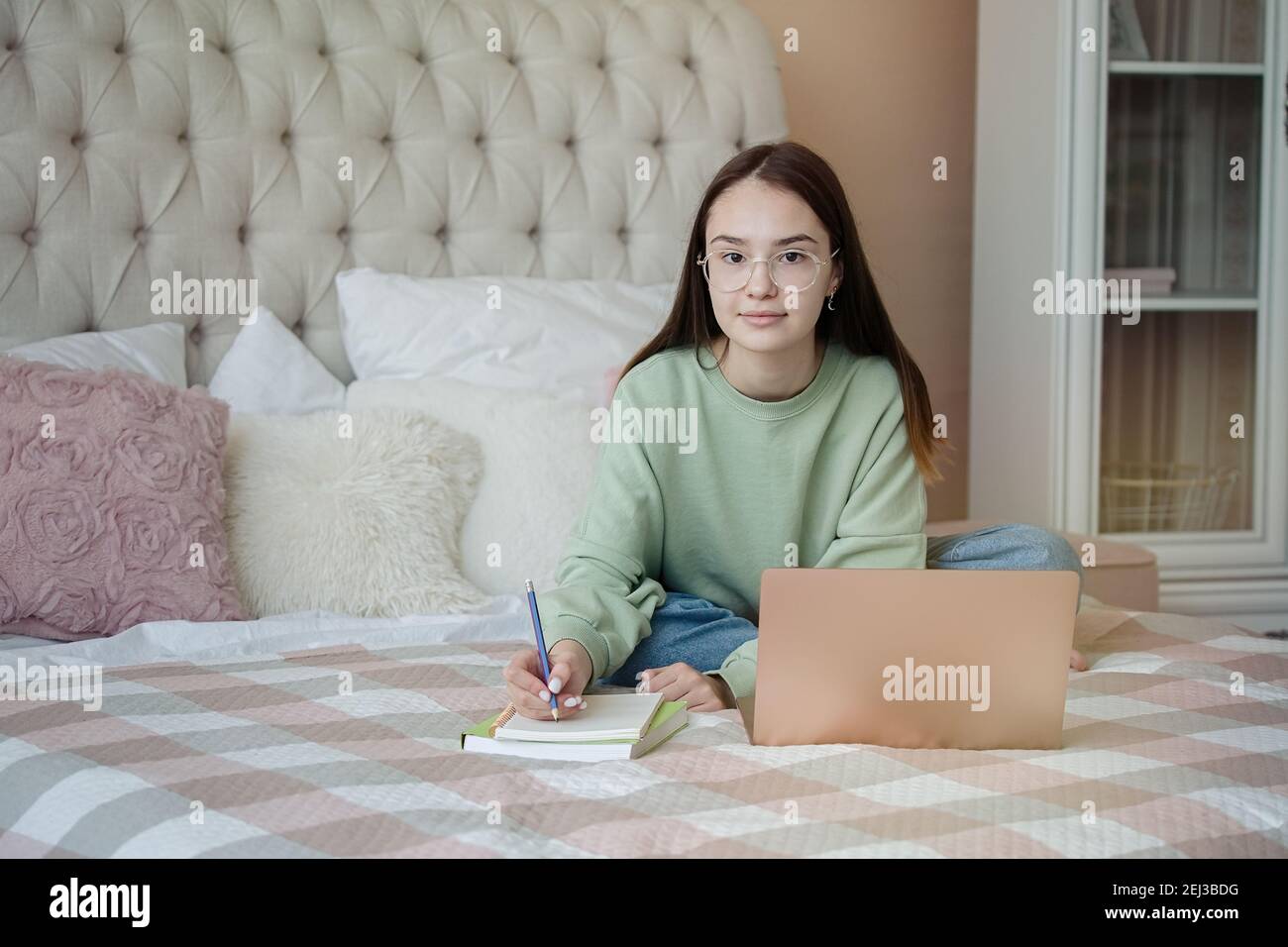 Cute teenager girl doing homework.Young girl wearing glasses writing ...