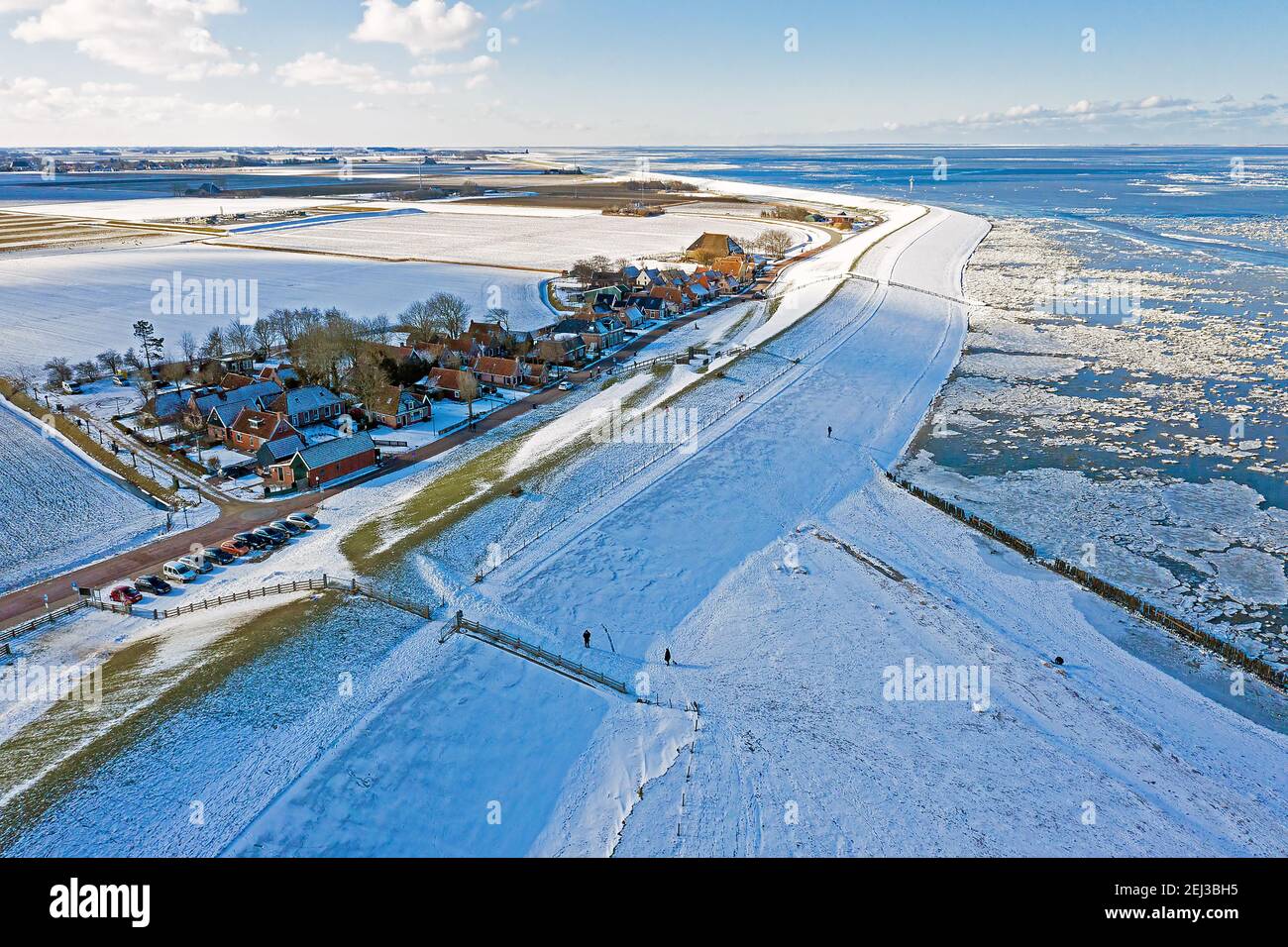 Aerial from snowy village Moddergat in Friesland at a frozen Waddensea ...