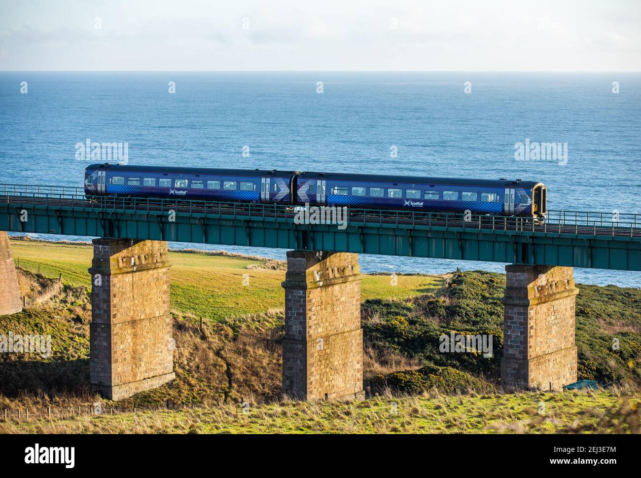 A passenger train on a railway line beside the sea in Scotland in the ...