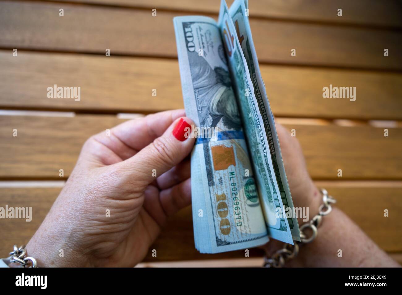 A top view of female hands counting dollar bills on a wooden background ...