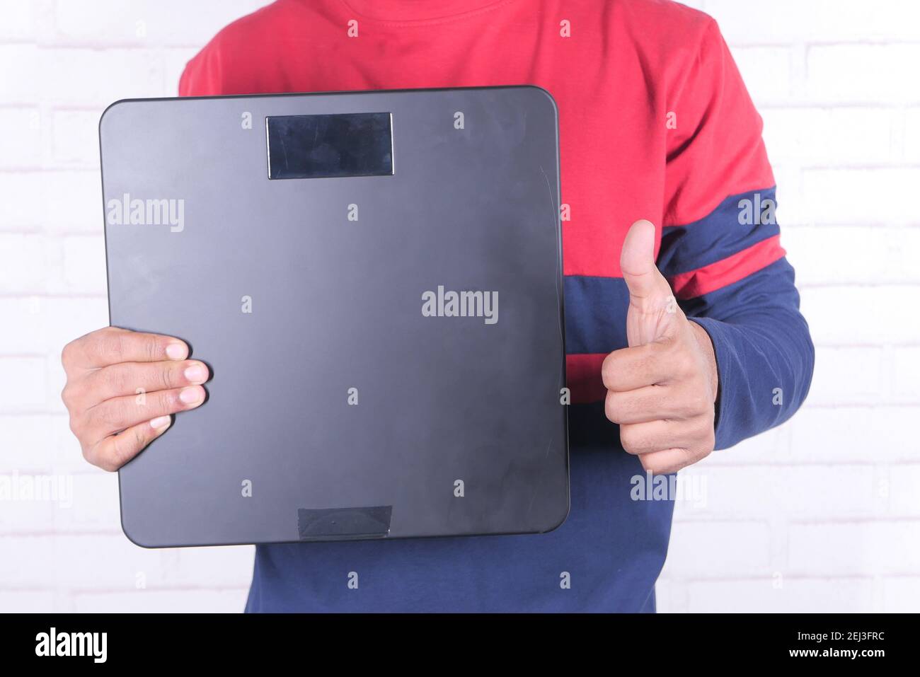young man holding weight machine doing thumbs up sign Stock Photo - Alamy