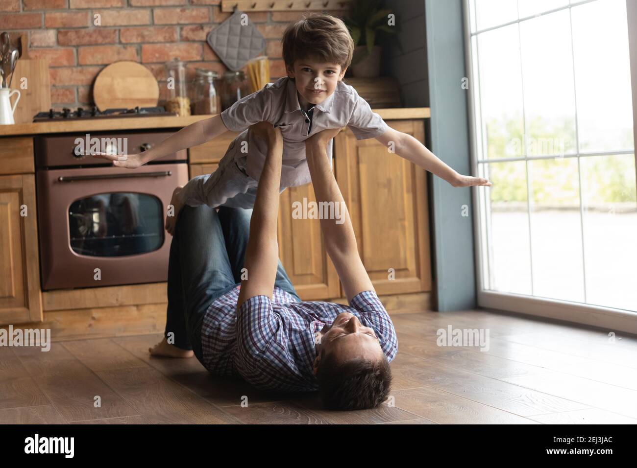 Portrait little boy pretending flying, playing fanny game with father ...