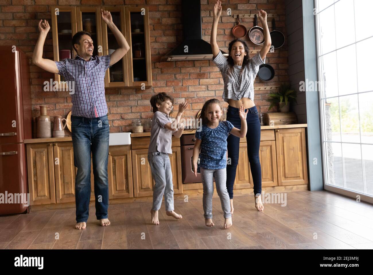 Overjoyed mother and father with little kids dancing in kitchen Stock ...