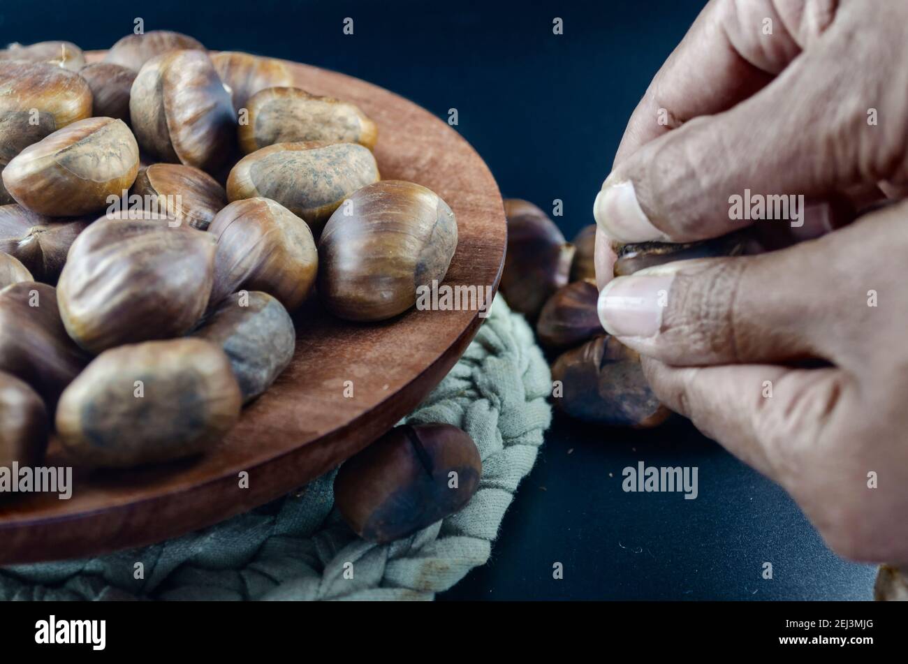 Hands of a black woman peeling a roasted chestnut Stock Photo - Alamy