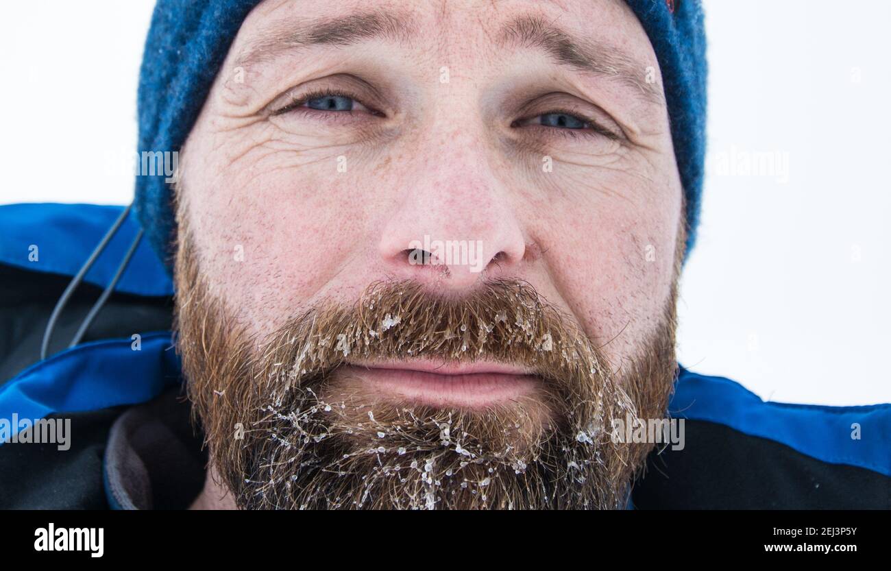 Portrait of the young man with frozen icy hairs on face and with beard ...