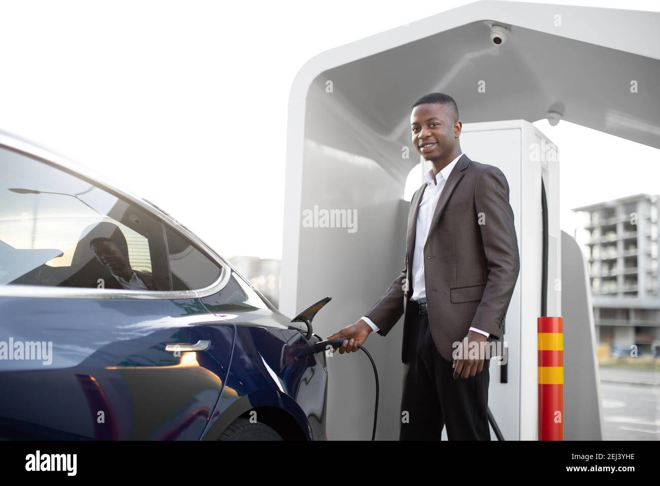 Electric cars, EV concept, eco friendly fuel. Portrait of young smiling ...