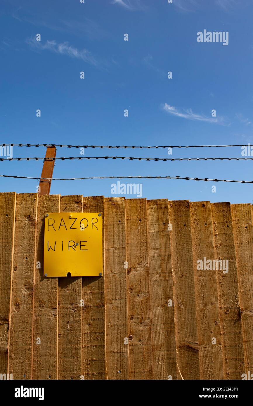 Razor wire sign on a wooden fence Stock Photo - Alamy