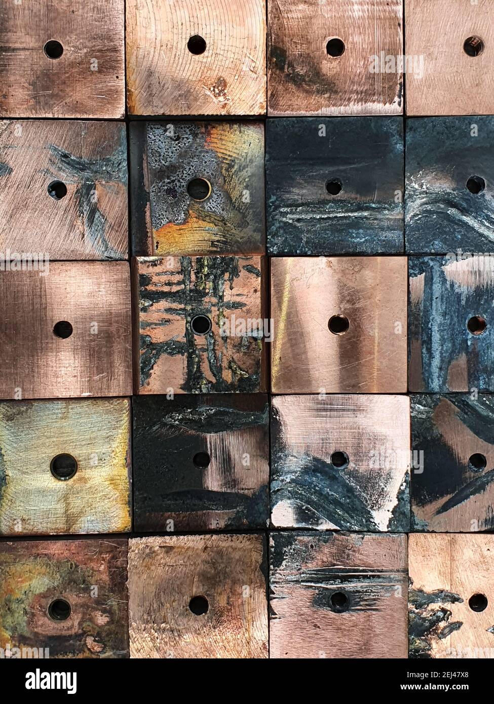 A vertical shot of piled stained brass with small holes in the middle ...