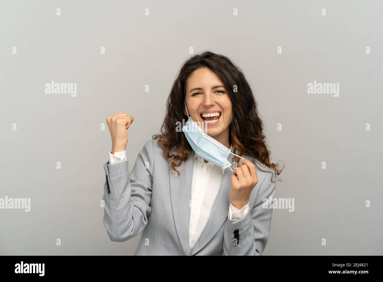 Studio portrait of happy business woman taking off mask from face ...