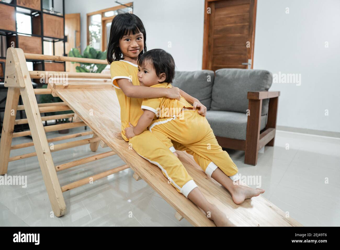 The siblings hug while playing slide in the Pikler Triangle Toy ...