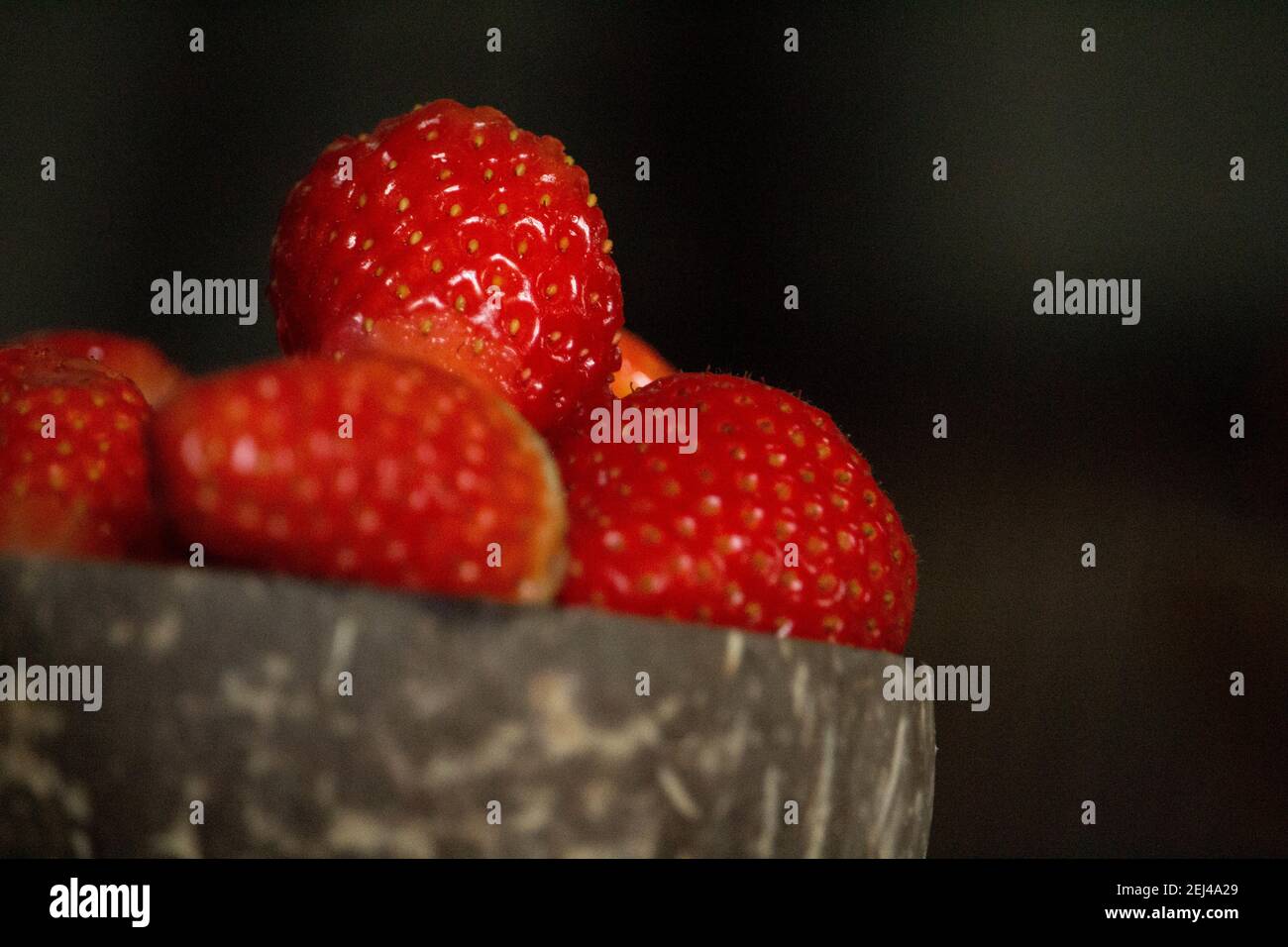 A closeup view of delicious-looking strawberries in a coconut bowl on a ...