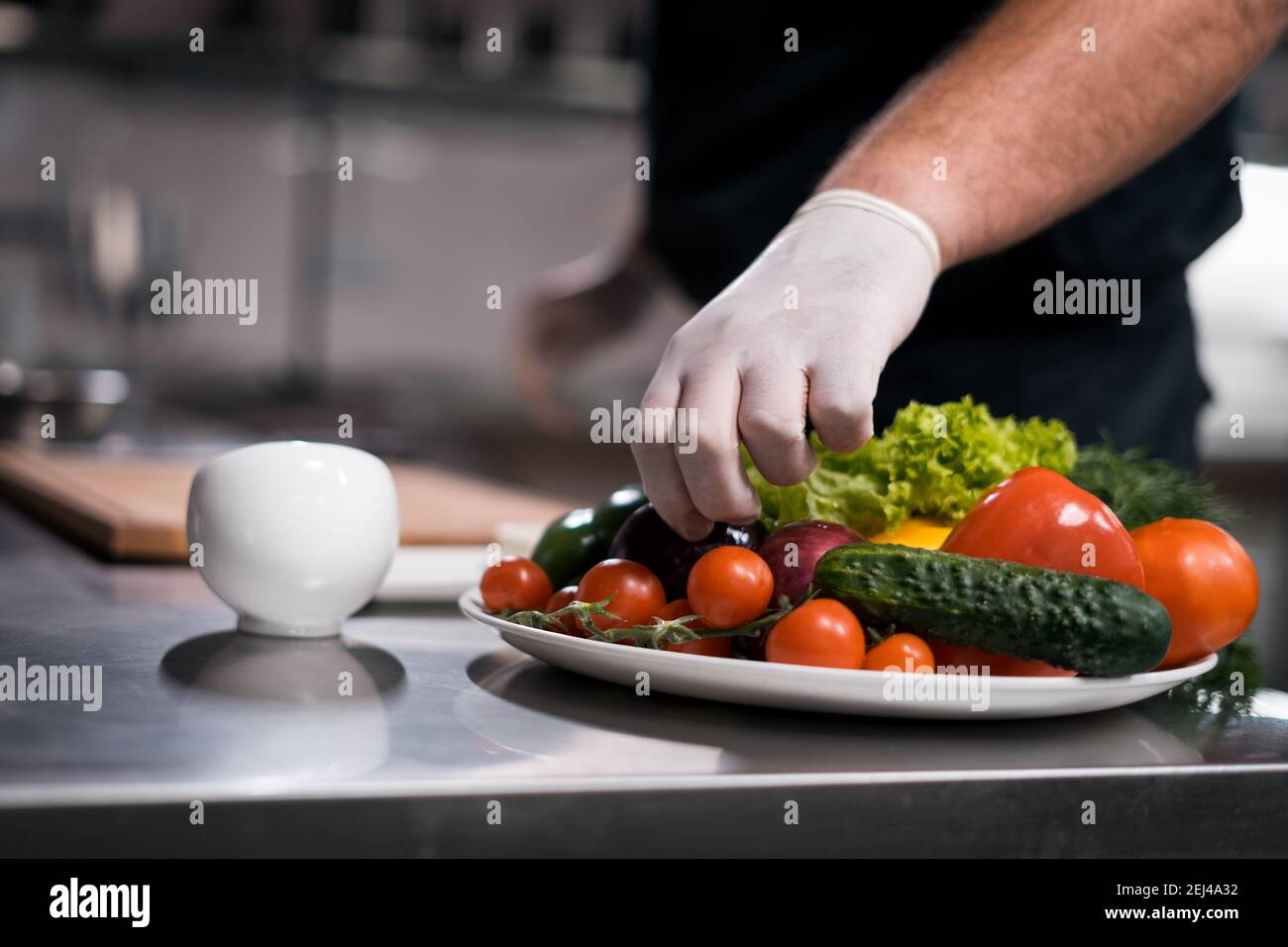 chef cook hands in medical gloves prepare greek salad with vegetables ...