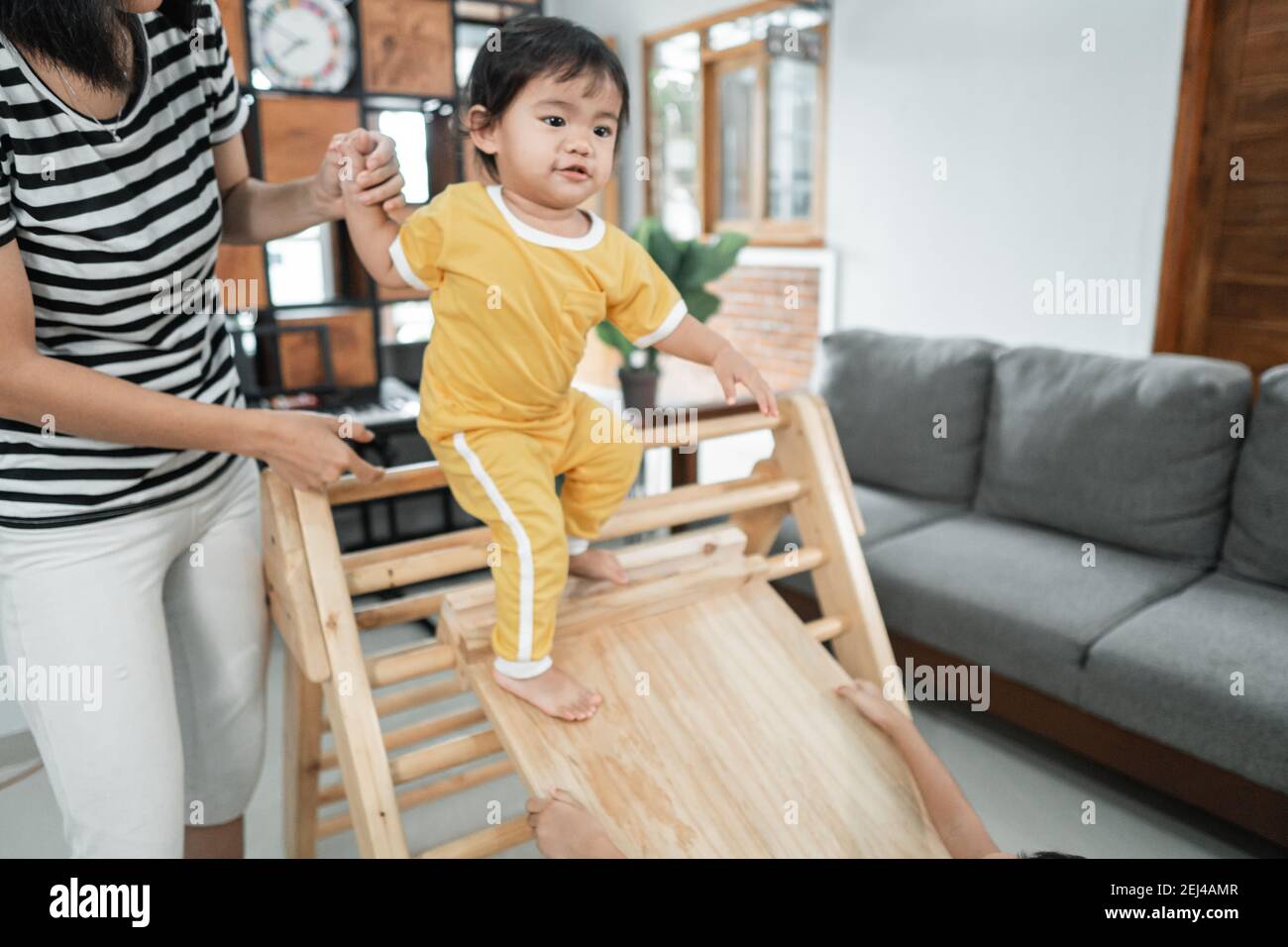 The baby standing will slide in the mother's hold on the Pikler ...