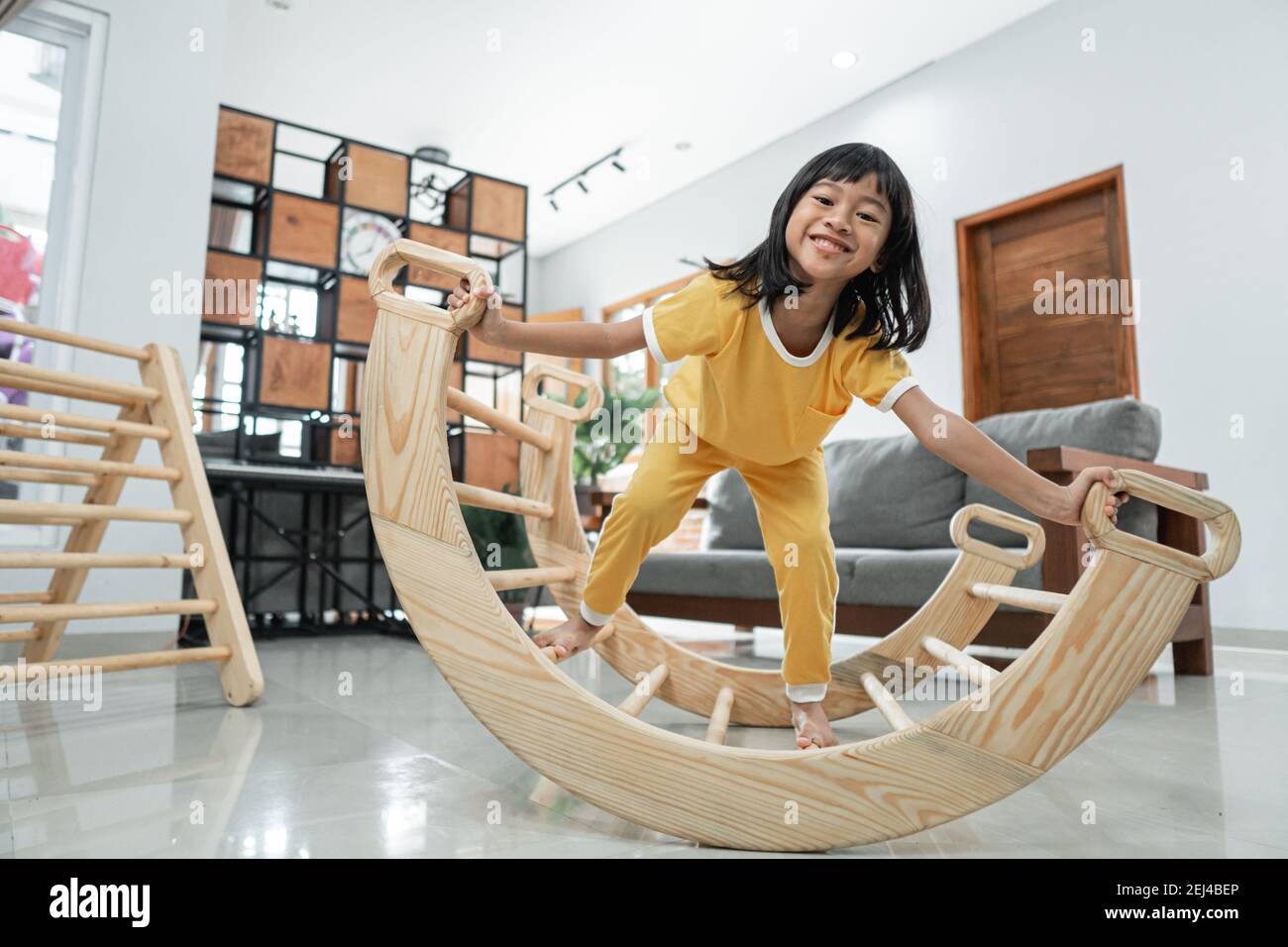 little girl smile while playing balance in pikler triangle toy at home ...