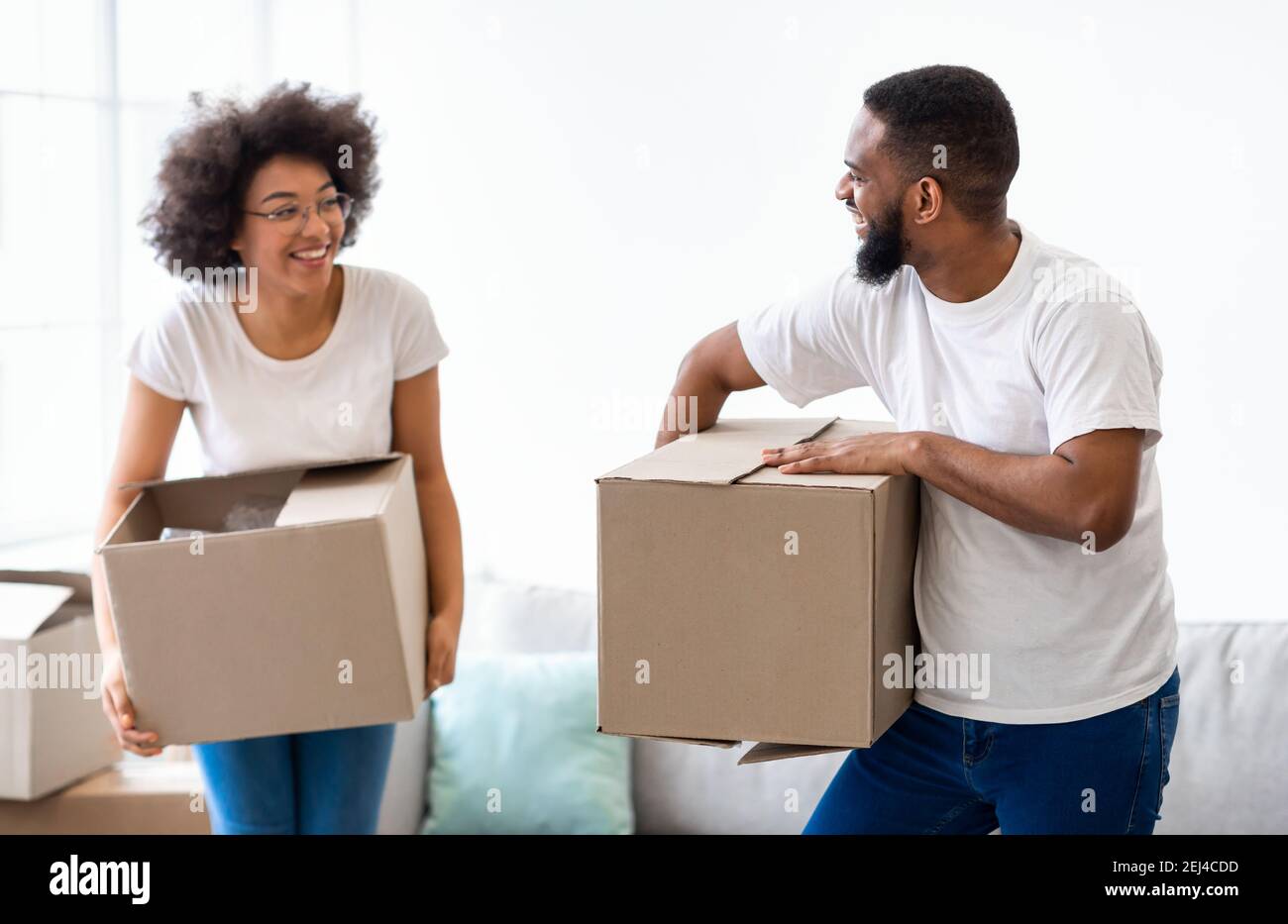 Joyful African Couple Laughing Carrying Moving Boxes Together Indoors ...