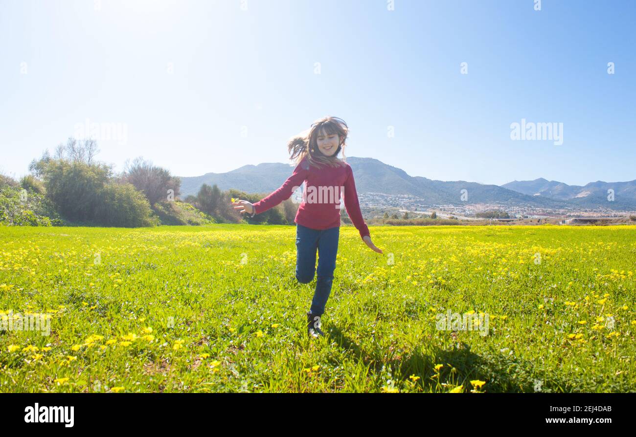 Image of a girl running through the field in a landscape full of yellow ...