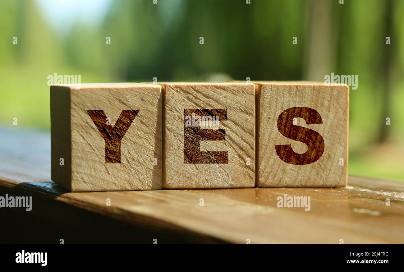 Yes word on three wooden cubes on nature background. Positive answer ...