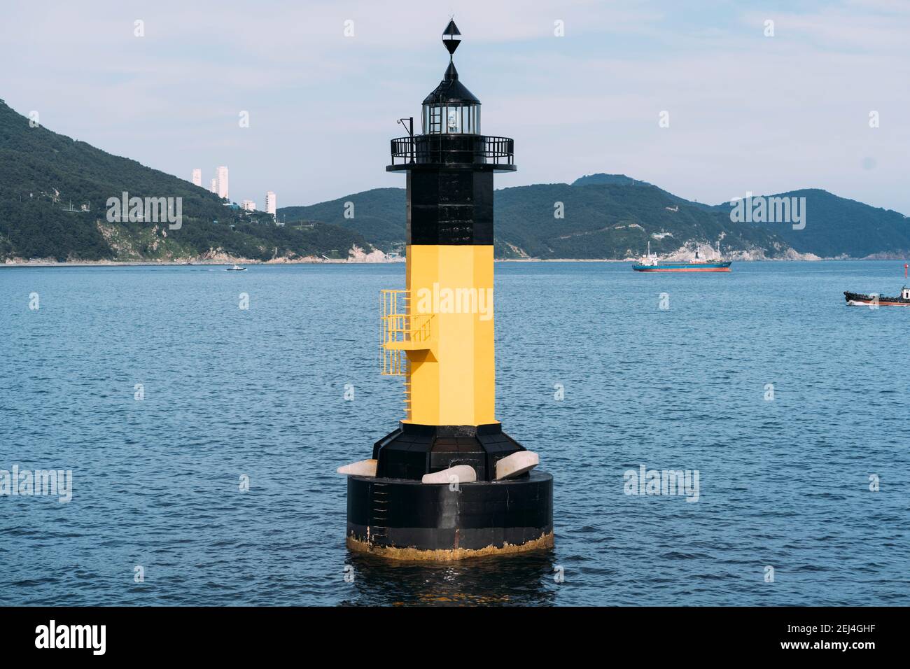 Landscape view of large, yellow and black painted lighthouse, floating ...
