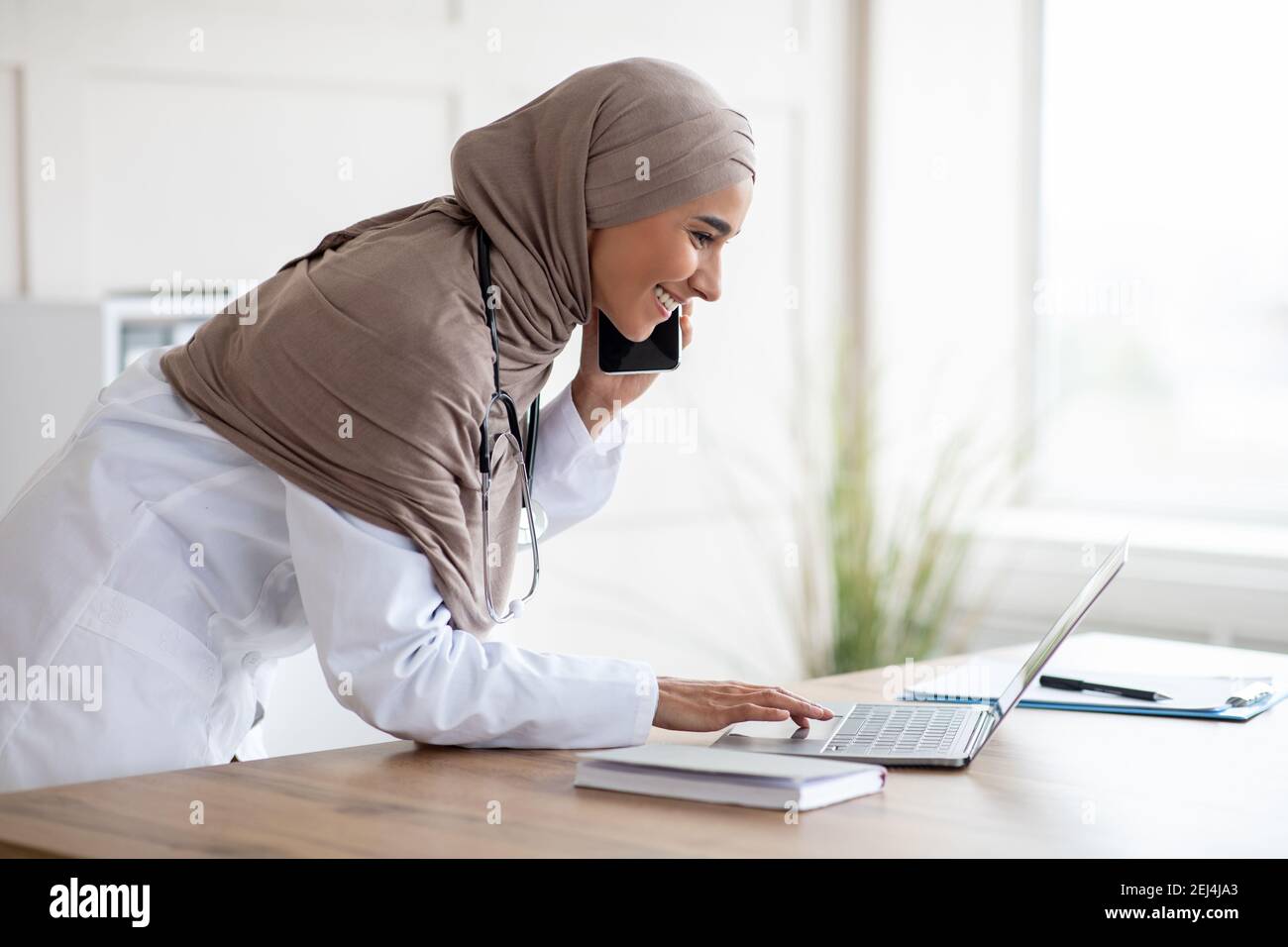 Side view of female doctor arranging appointment on phone Stock Photo ...
