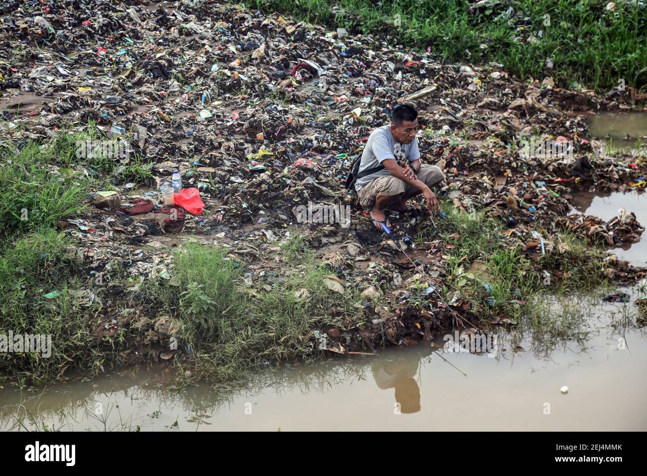 A man is seen fishing on a riverbank piled with garbage after the ...