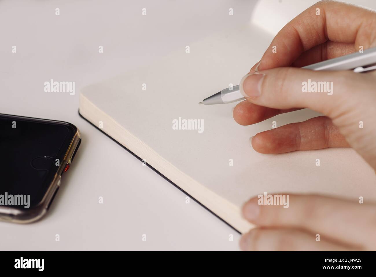 A male is working. Making notes. Smartphone is on a desk Stock Photo ...