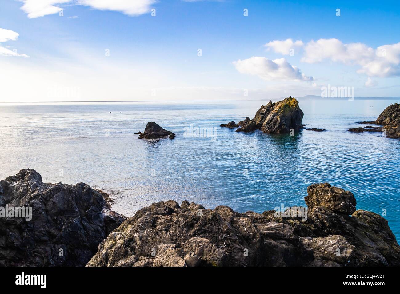 Rocks protruding from the surrounding blue ocean waters Stock Photo - Alamy
