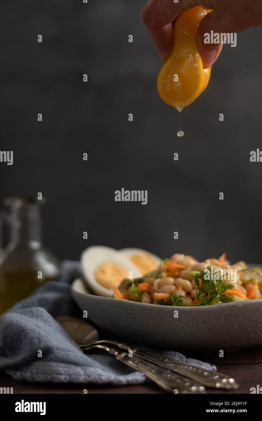 Squeeze lemon over cooked bean salad Stock Photo - Alamy