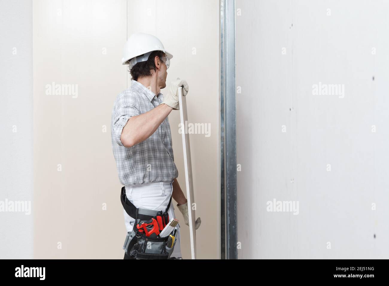man drywall worker installing plasterboard sheet to wall. Wearing ...