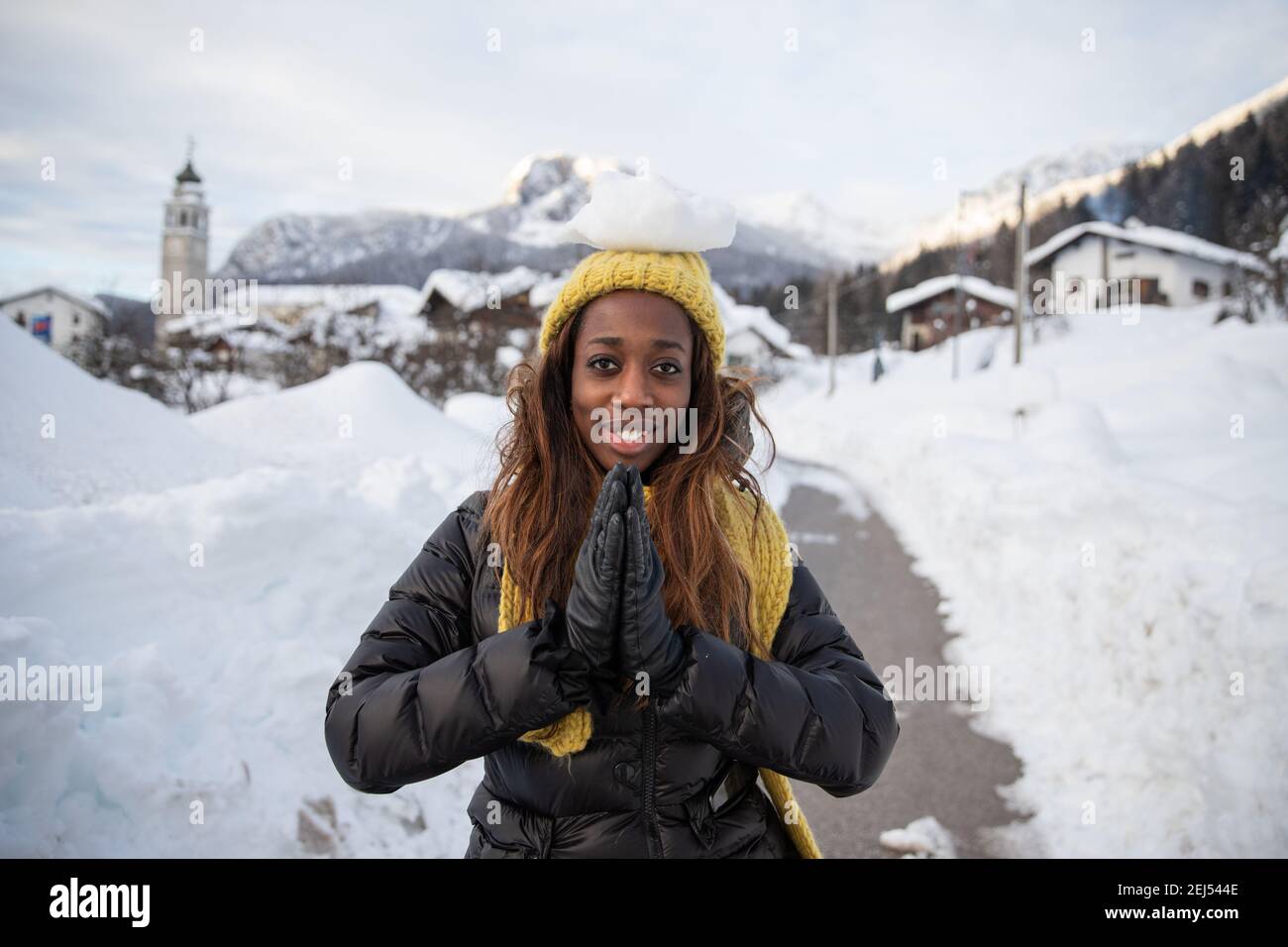 A pretty black girl poses smiling with a snowball above her head and ...