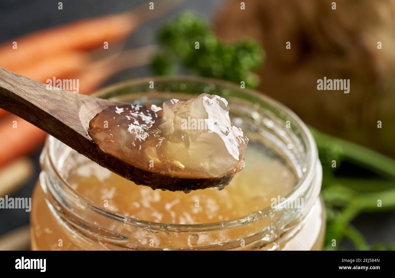 Cooled jellied beef bone broth on a spoon and in a glass jar Stock ...