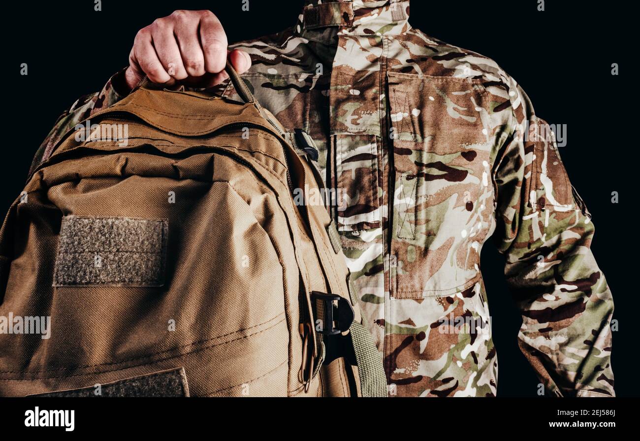 Photo of soldier in camouflaged uniform and tactical gloves holding ...