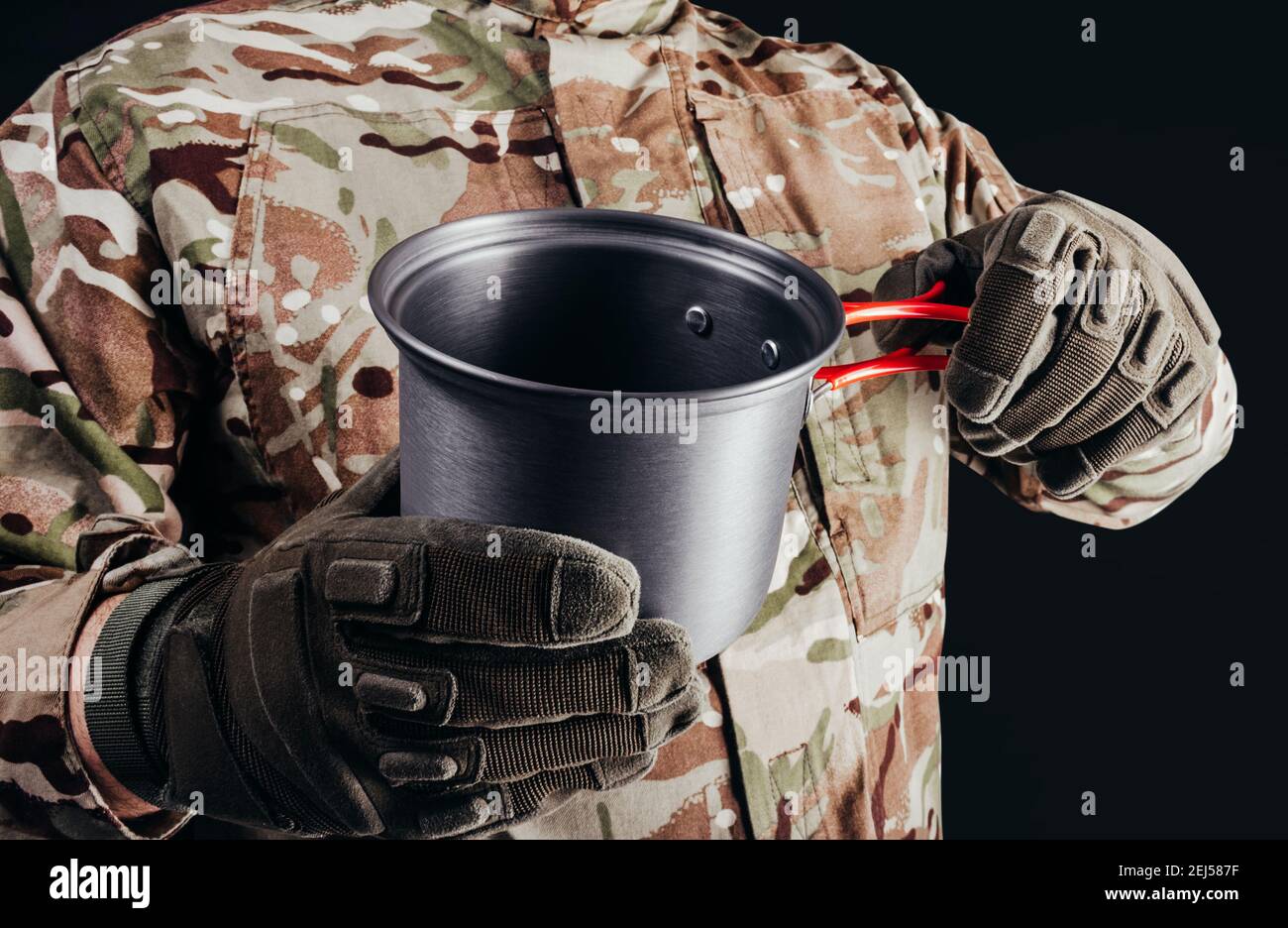 Photo of soldier in camouflaged uniform and tactical gloves holding ...