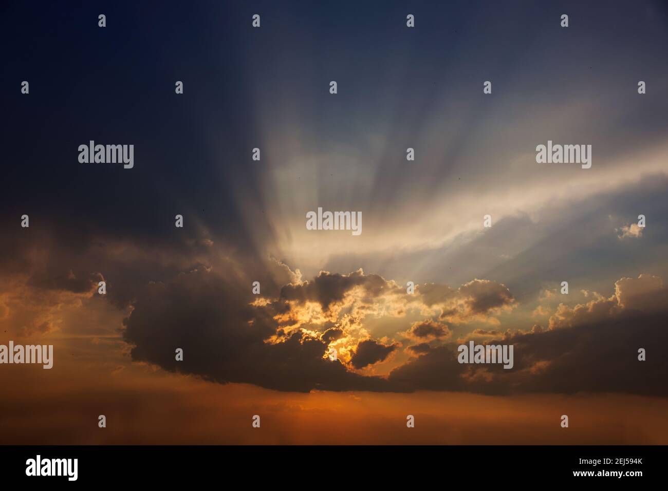 natural background of the sun setting behind a cloud and with sunbeams ...