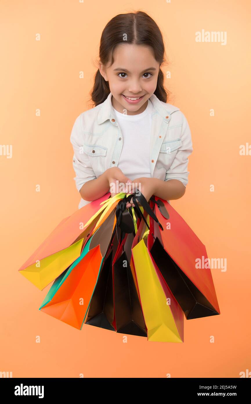 Kid girl happy smiling face carries bunch packages yellow background ...