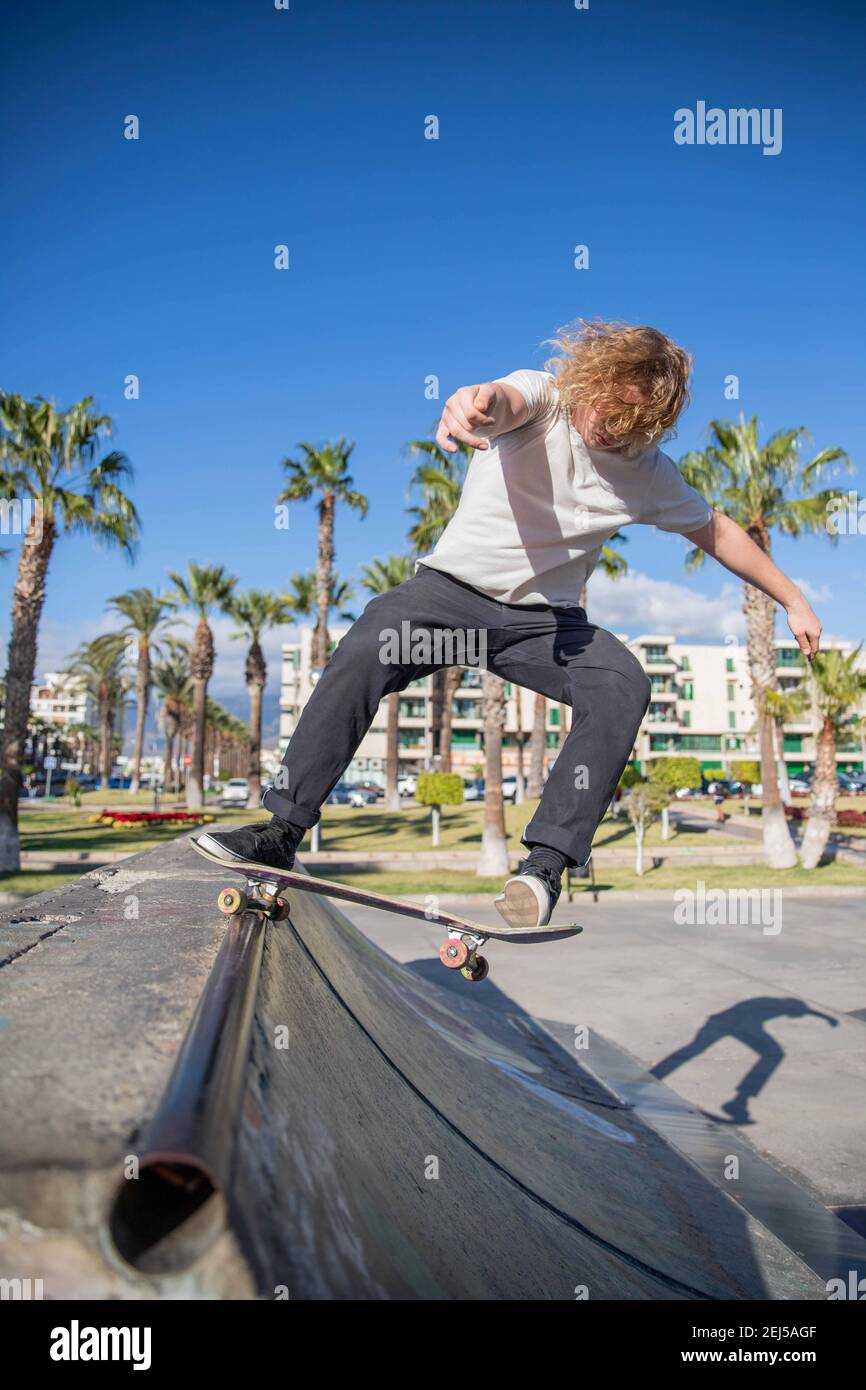 Skater rolls down the ramp with his skateboard in a tropical location ...