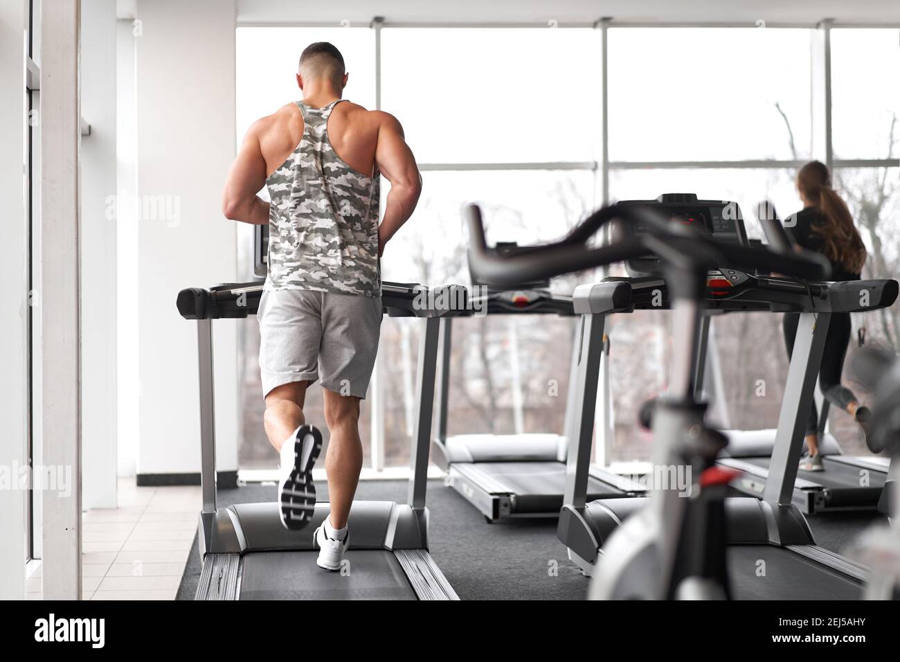 Muscular athletic bodybuilder fitness model running treadmill gym near ...