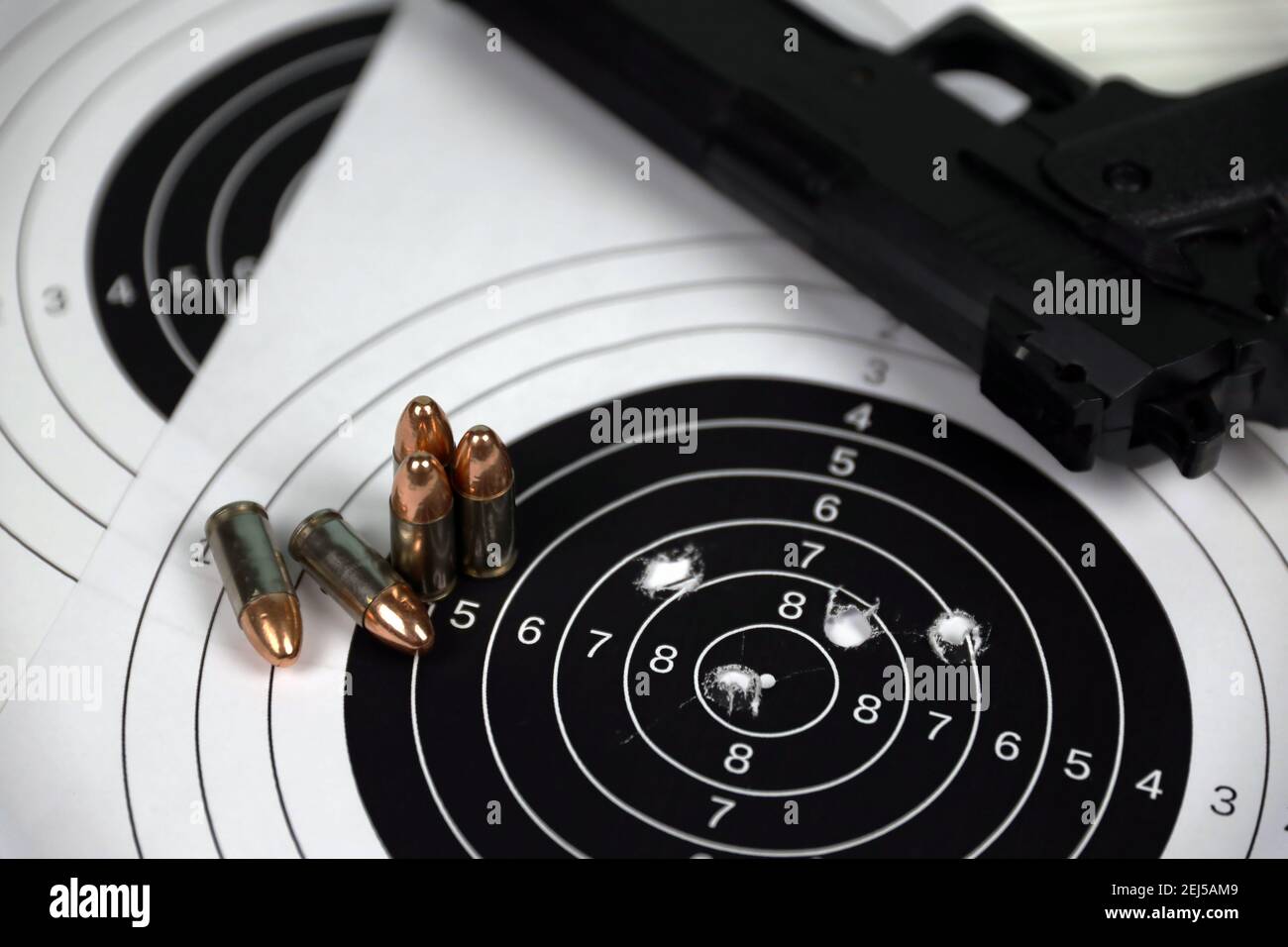Gun and many bullets shooting targets on white table in shooting range ...