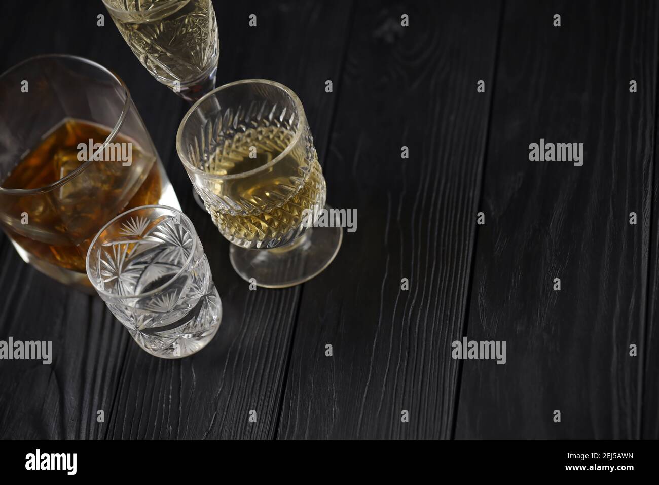 Different alcohol drinks in glass on wooden surface on dark background ...