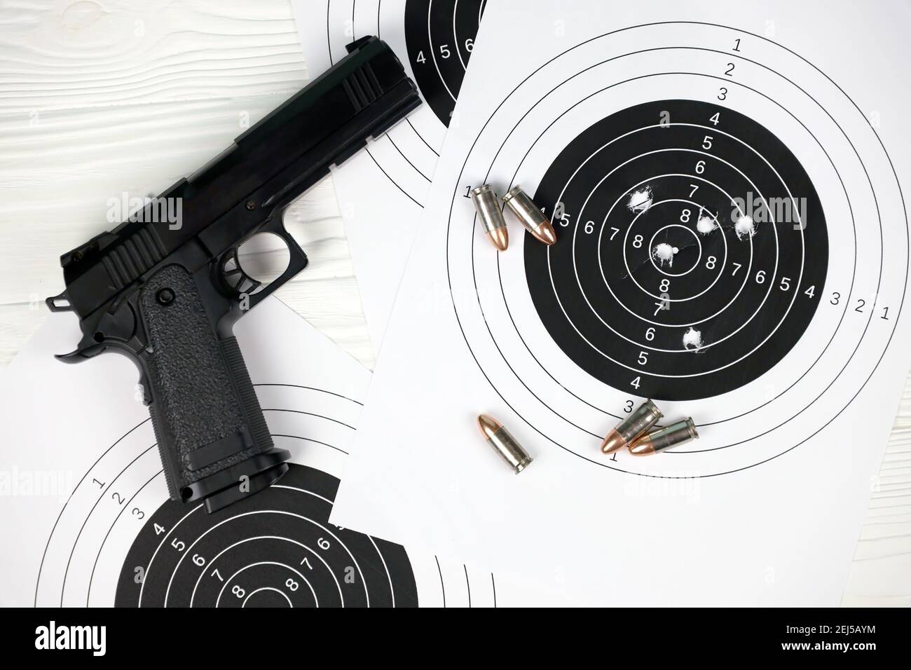 Gun and many bullets shooting targets on white table in shooting range ...
