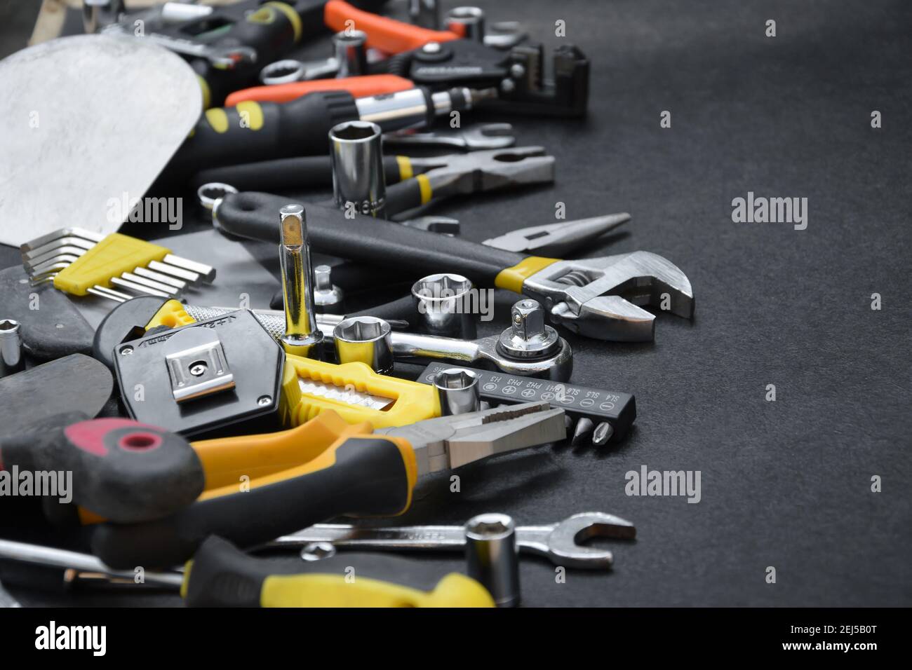 Handyman tool kit on black wooden table. Many wrenches and screwdrivers ...