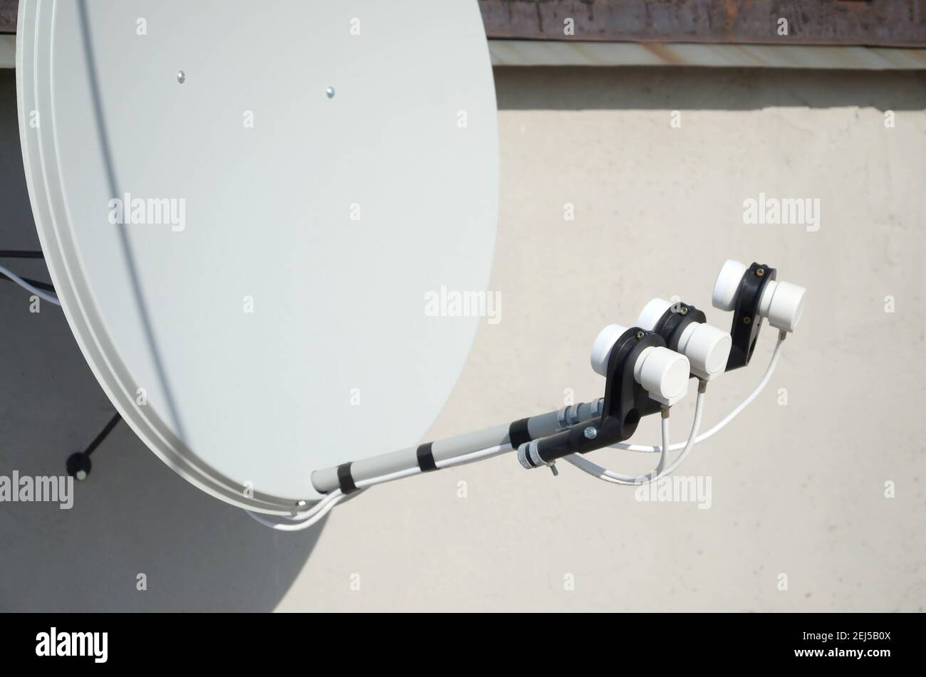 White satellite dish with three converters mounted on residental ...