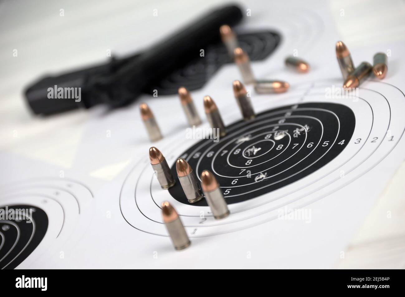 Gun and many bullets shooting targets on white table in shooting range ...