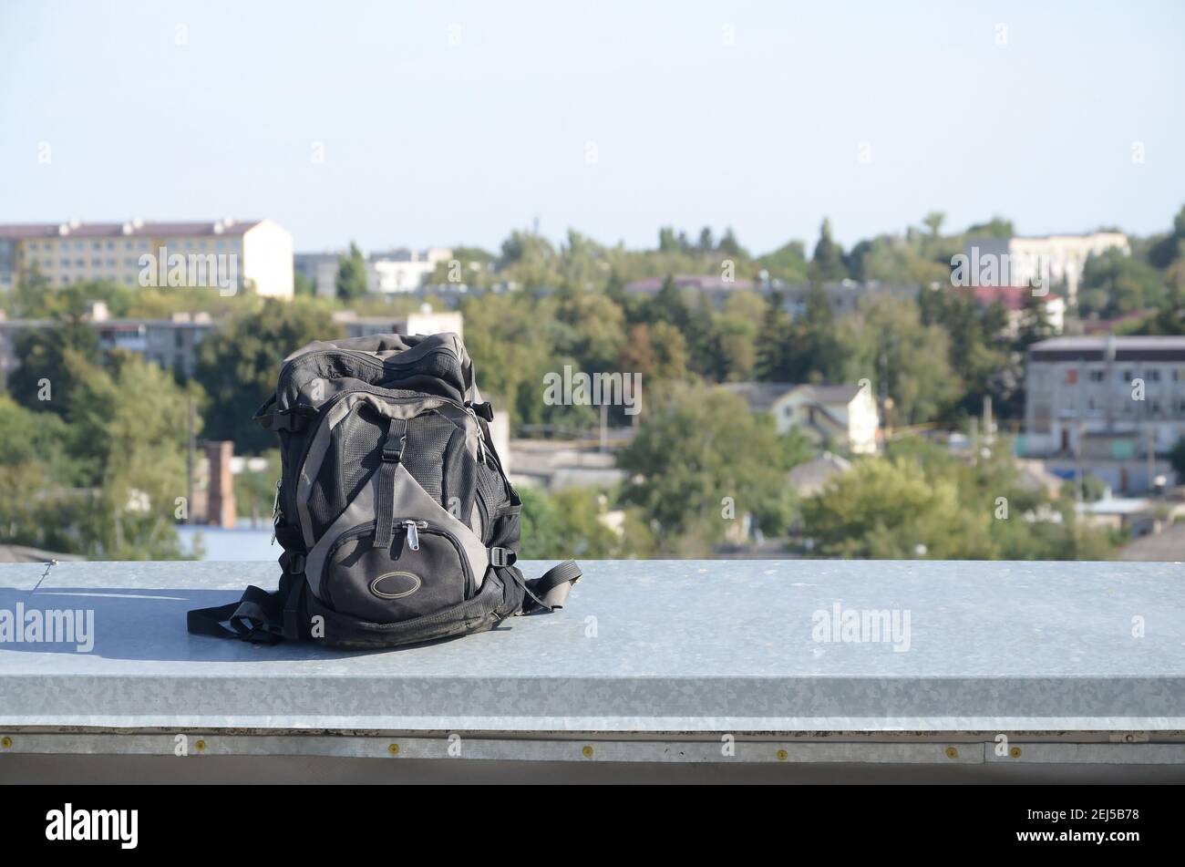 Black backpack lies on metal border of residental multistorey building ...