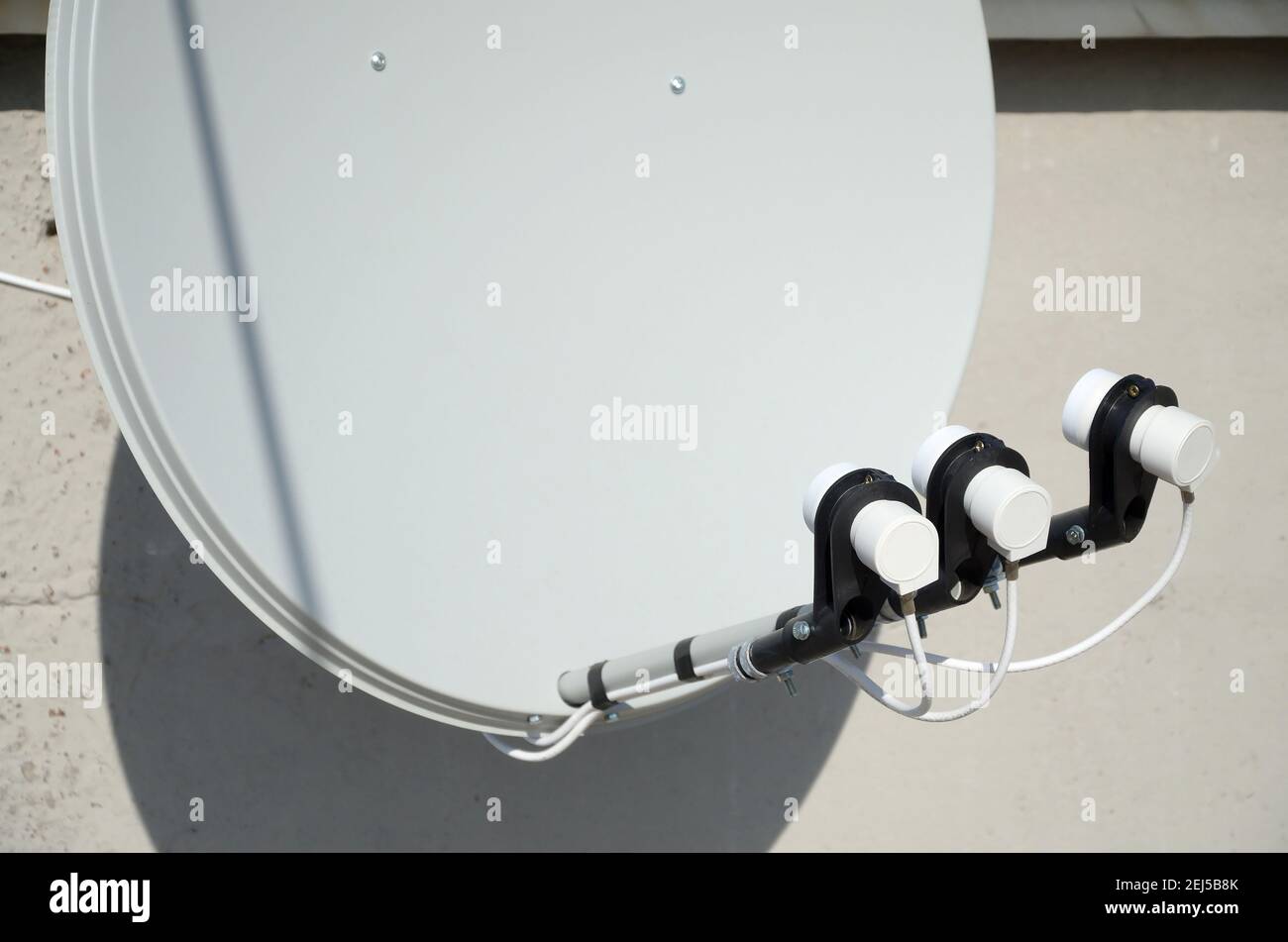 White satellite dish with three converters mounted on residental ...