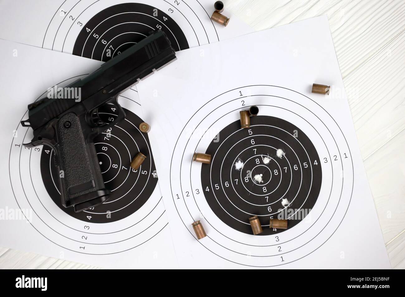 Gun and many bullets shooting targets on white table in shooting range ...
