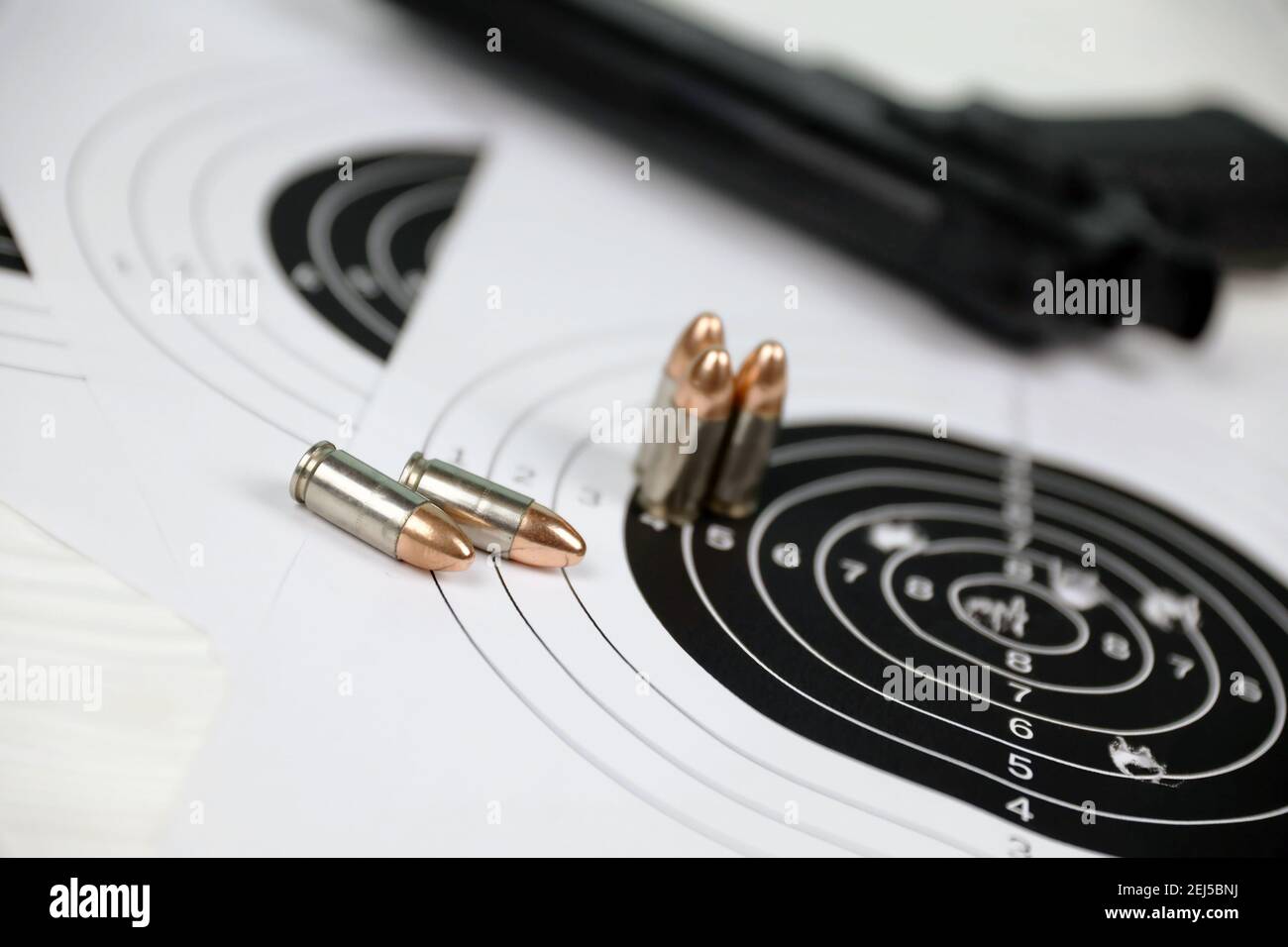 Gun and many bullets shooting targets on white table in shooting range ...