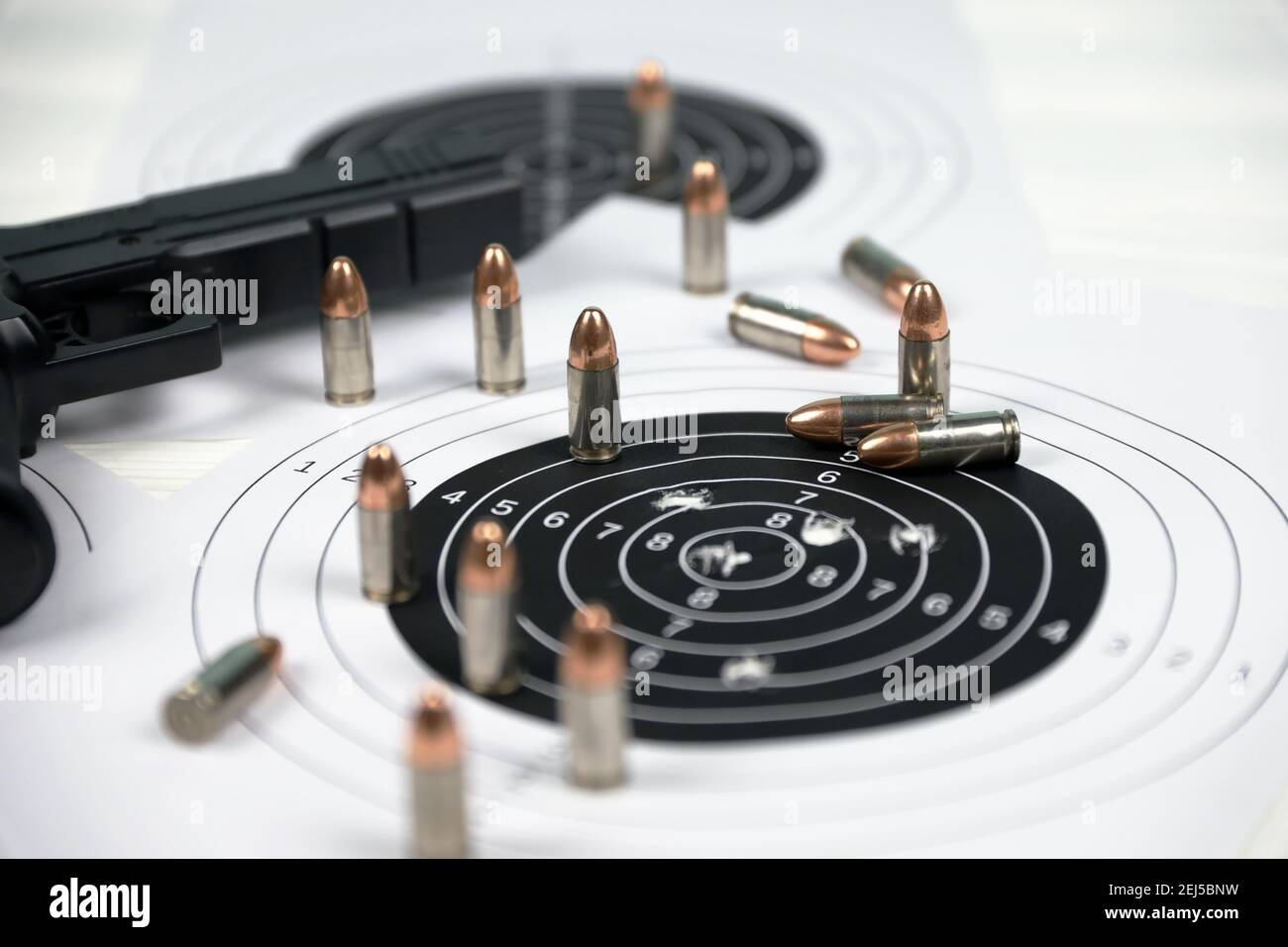 Gun and many bullets shooting targets on white table in shooting range ...