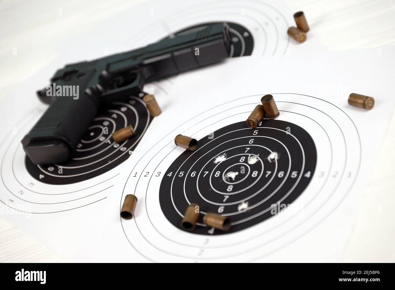 Gun and many bullets shooting targets on white table in shooting range ...
